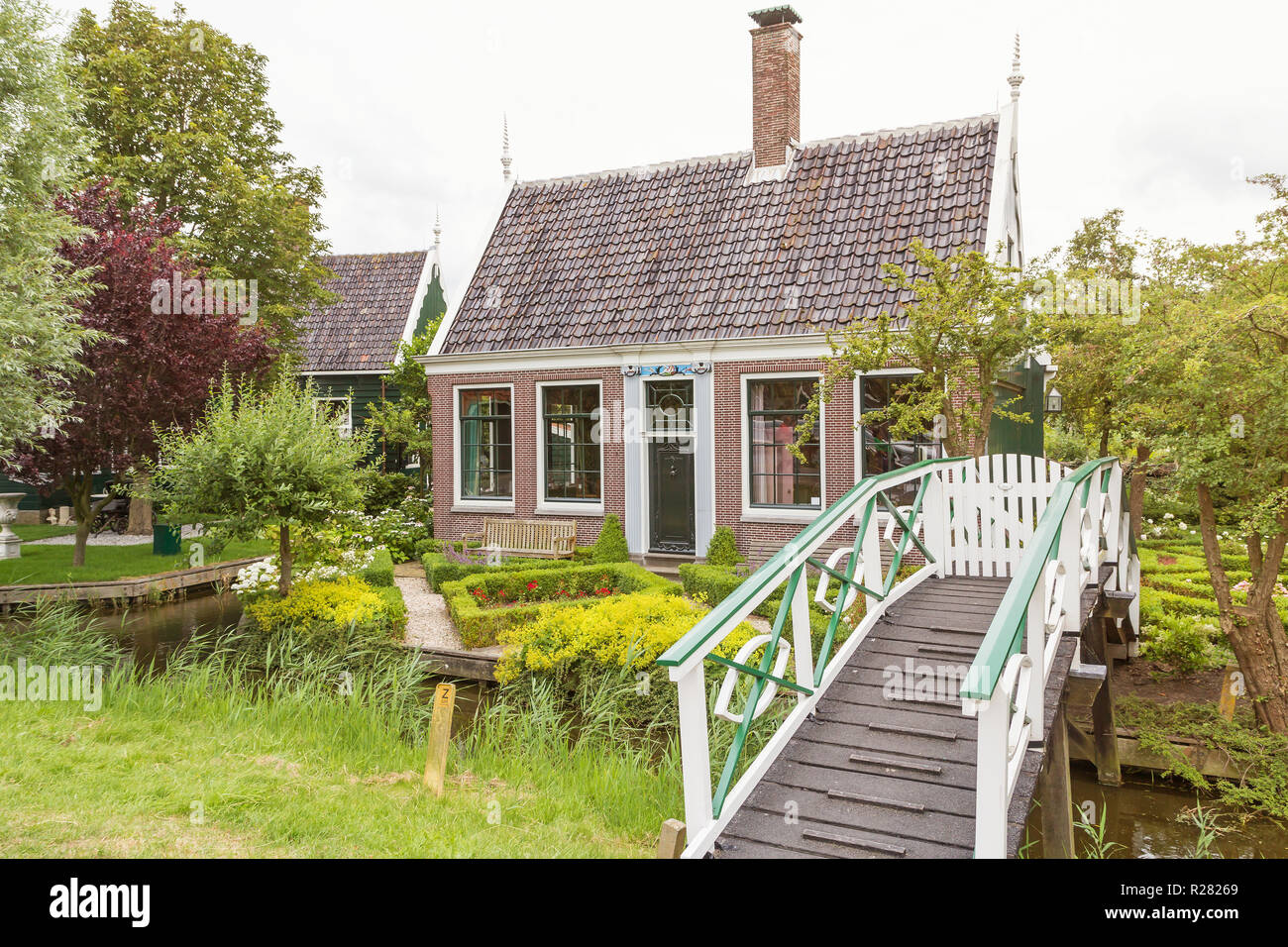 Typical Dutch brick house with water channel, garden and wooden bridge ...