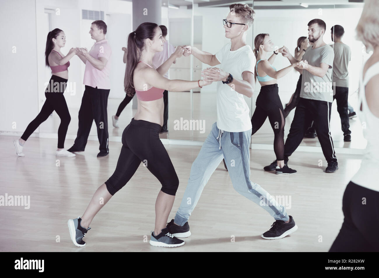 Cheerful positive smiling people of different ages having dancing class ...