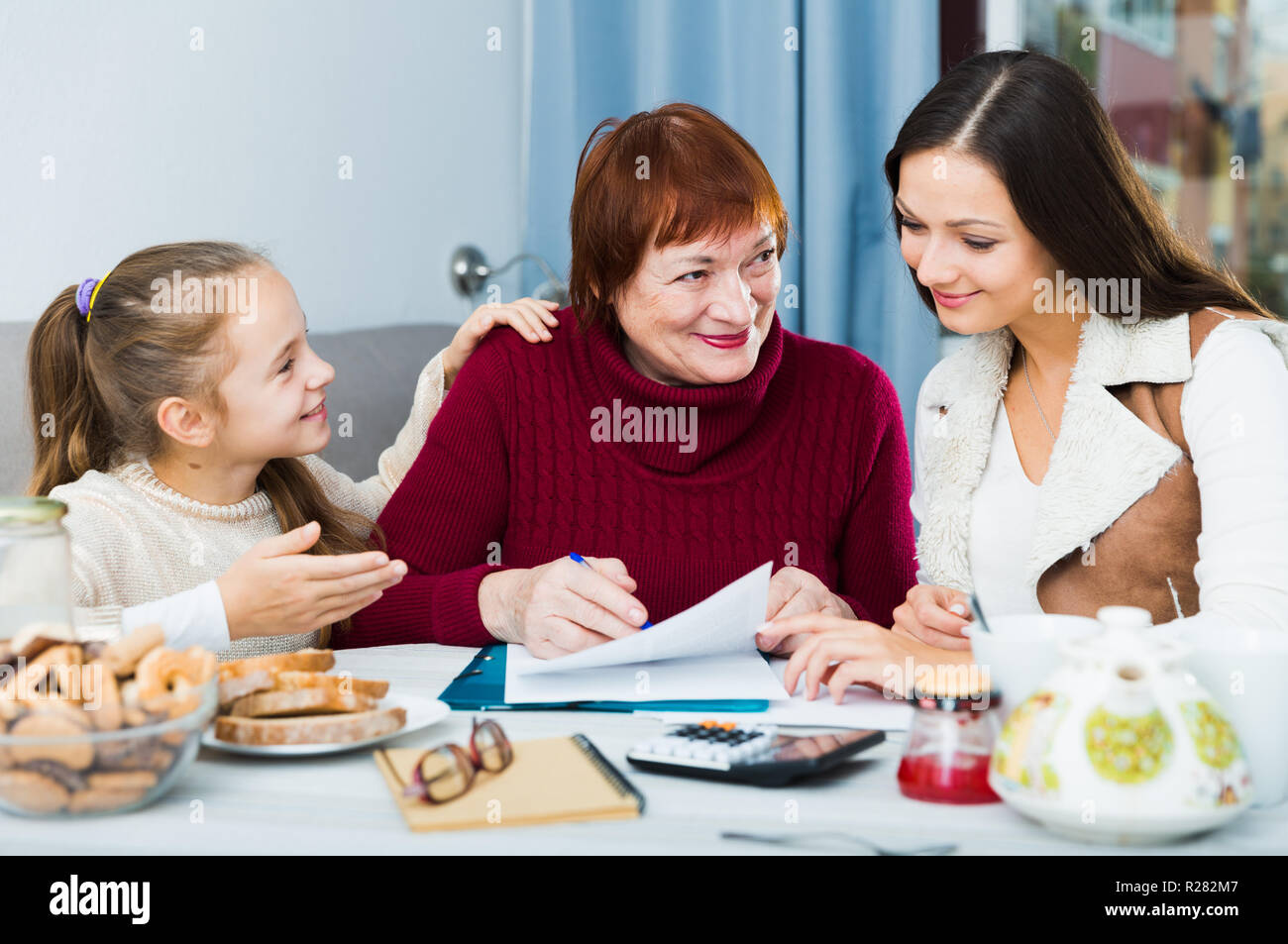 Three generations of happy family working together with documents at ...