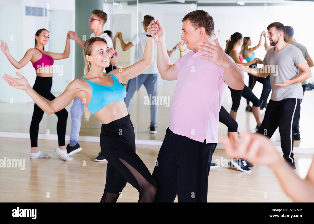 dancing couples of positive men and women learning swing at dance class ...