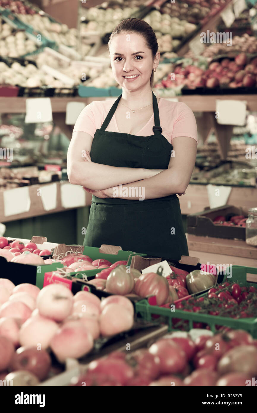 attractive salesgirl standing near fresh fruits and vegetables in ...