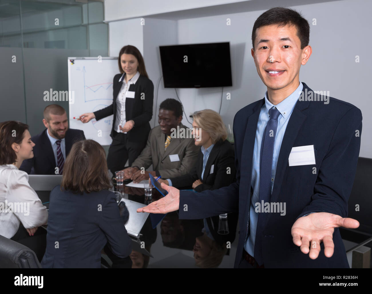 Positive chinese business man inviting to meeting room with people ...