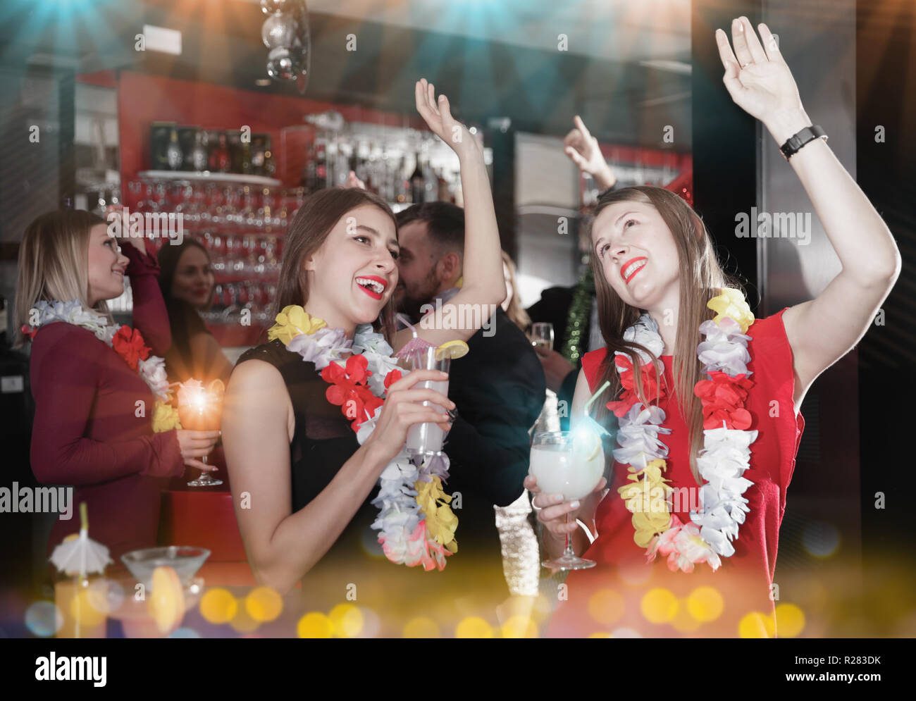 Happy young female colleagues enjoying company party in Hawaiian style ...