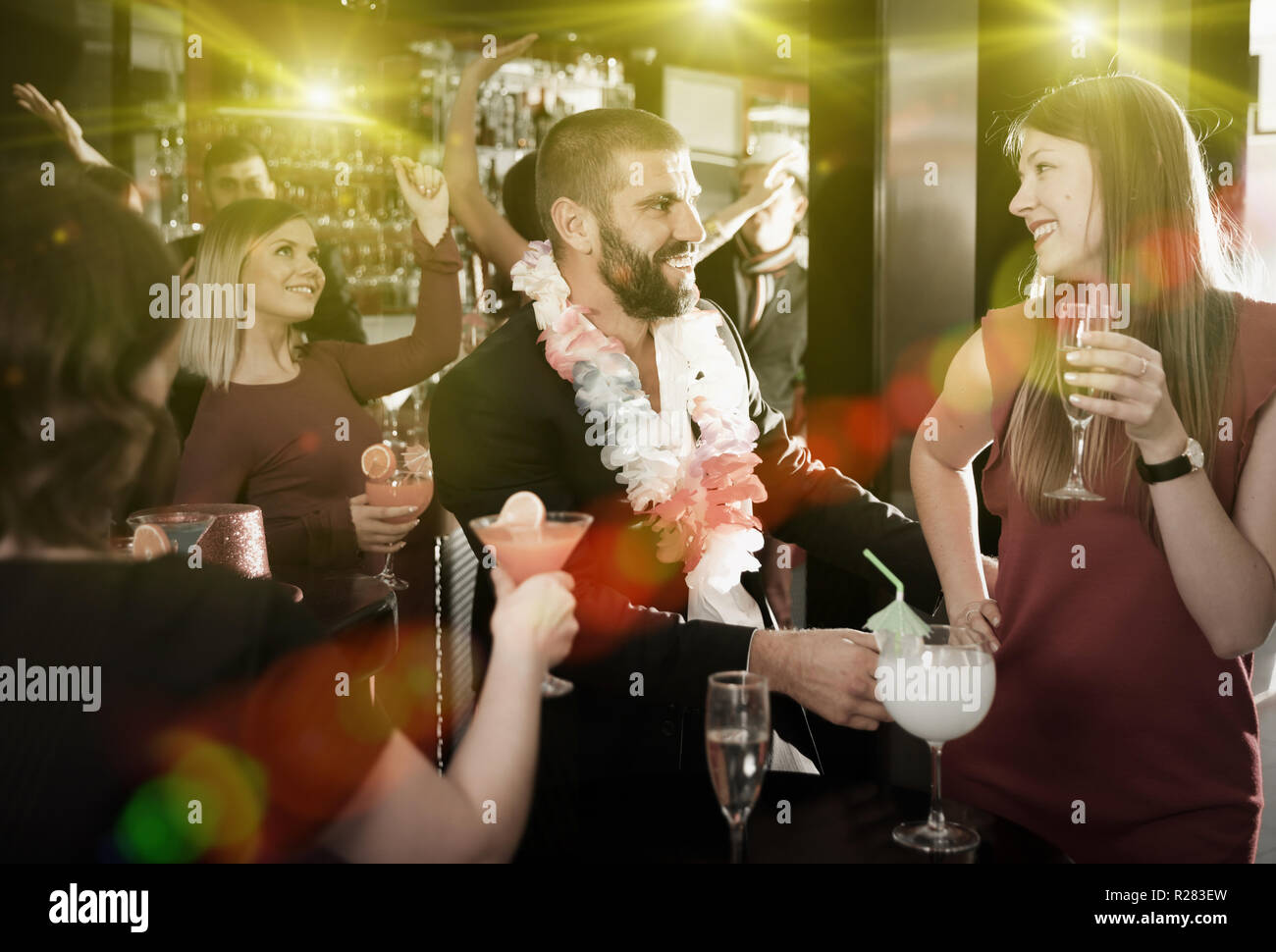 Young man with female colleague enjoying corporate party in Hawaiian ...
