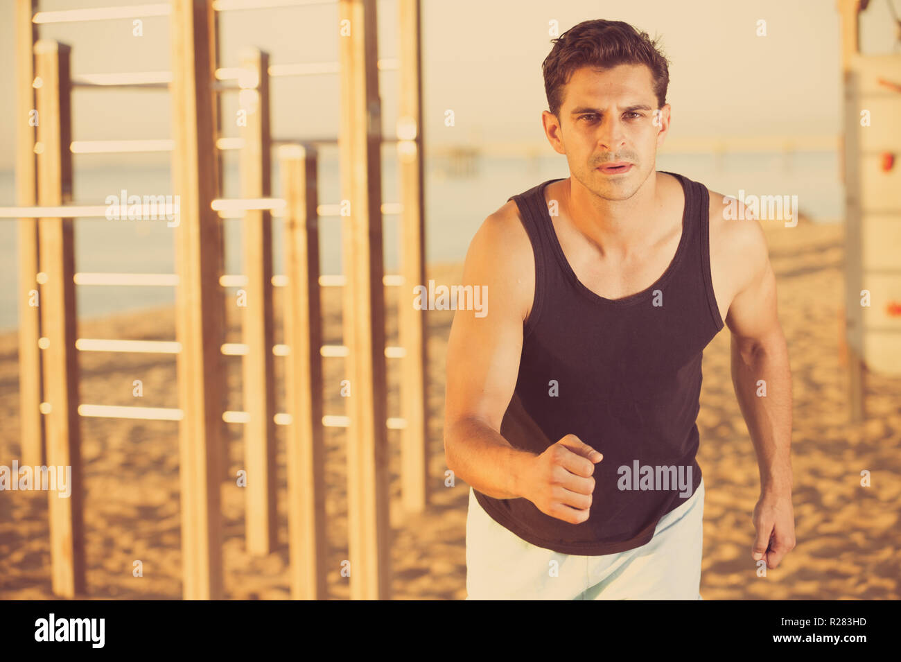 Serious strong man jogging during outdoor workout on beach Stock Photo ...