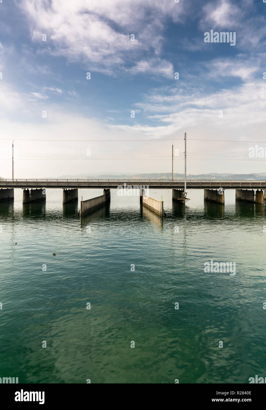 vertical view of a concrete bridge over water with a train line and ...