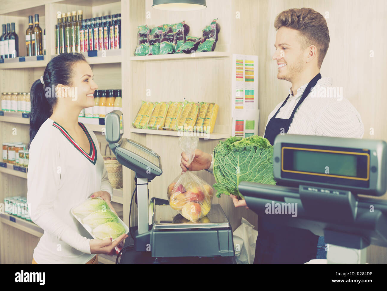 Male shopping assistant helping customer to weigh purchases at the ...