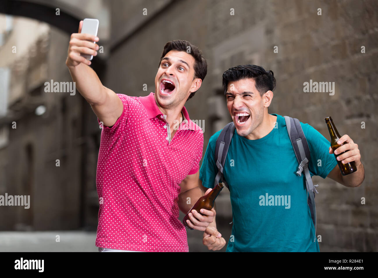 happy male fans are walking with beer and making selfie near sights in ...