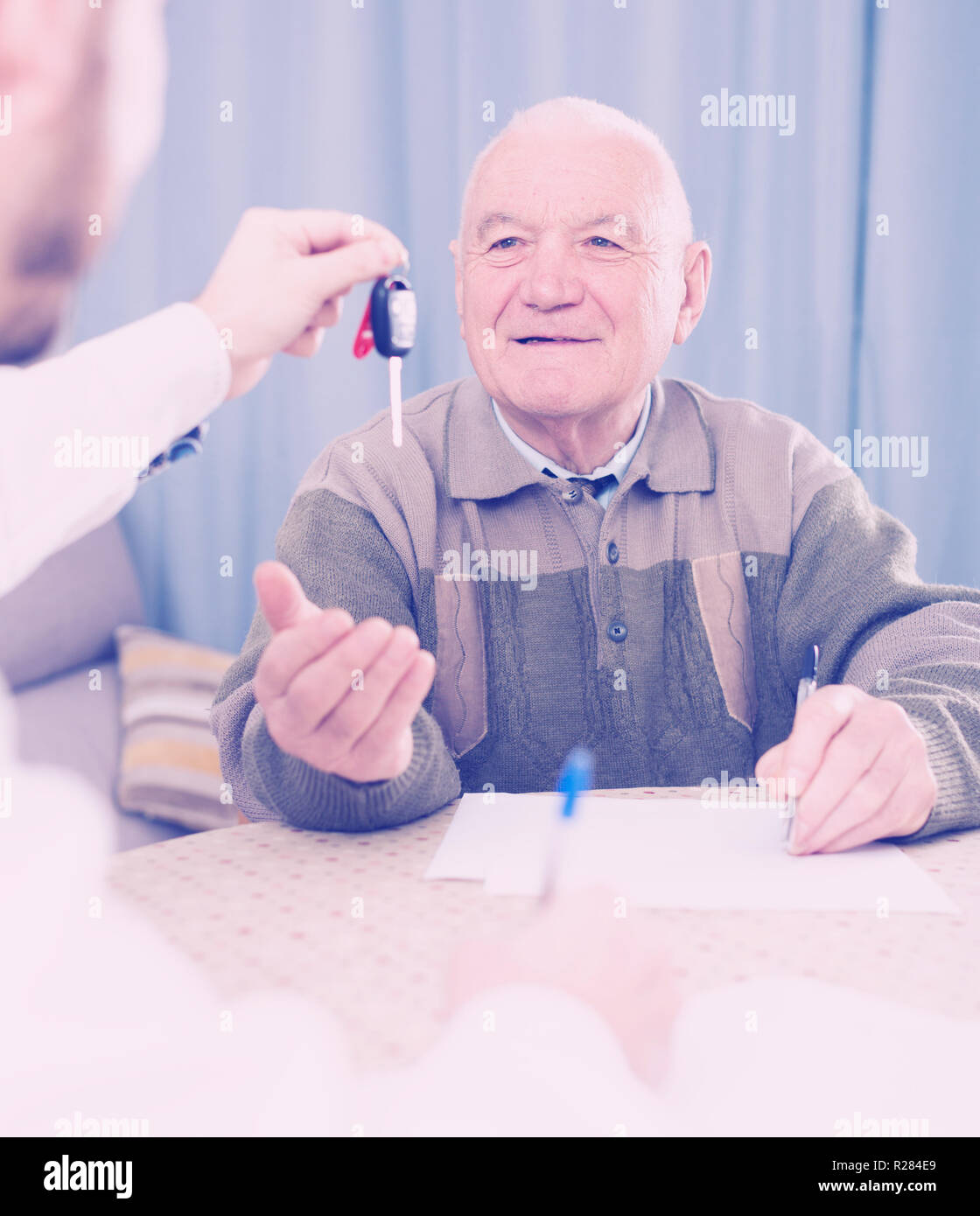 Old smiling man signing new car papers at home Stock Photo - Alamy