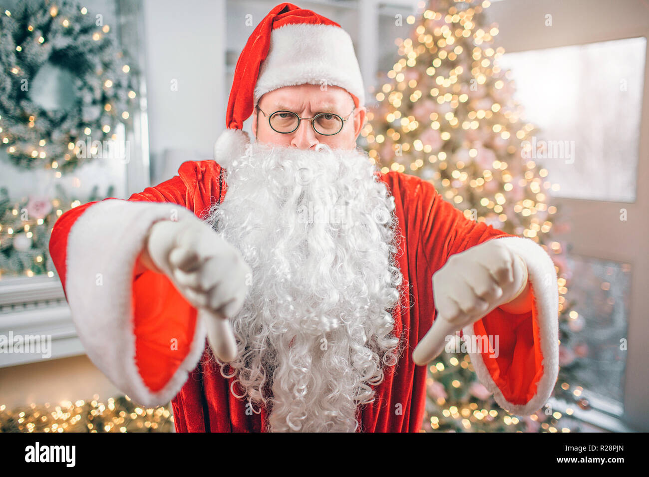 Angry old Santa Claus looks on camera and shows big thumbs down. Man is ...