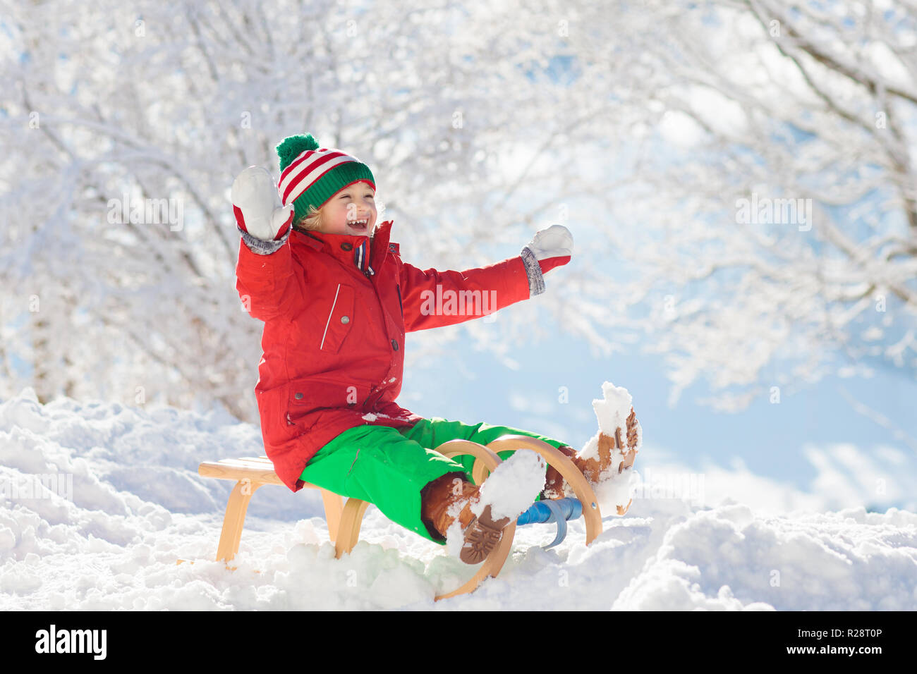 Little boy enjoying a sleigh ride. Child sledding. Toddler kid riding a ...