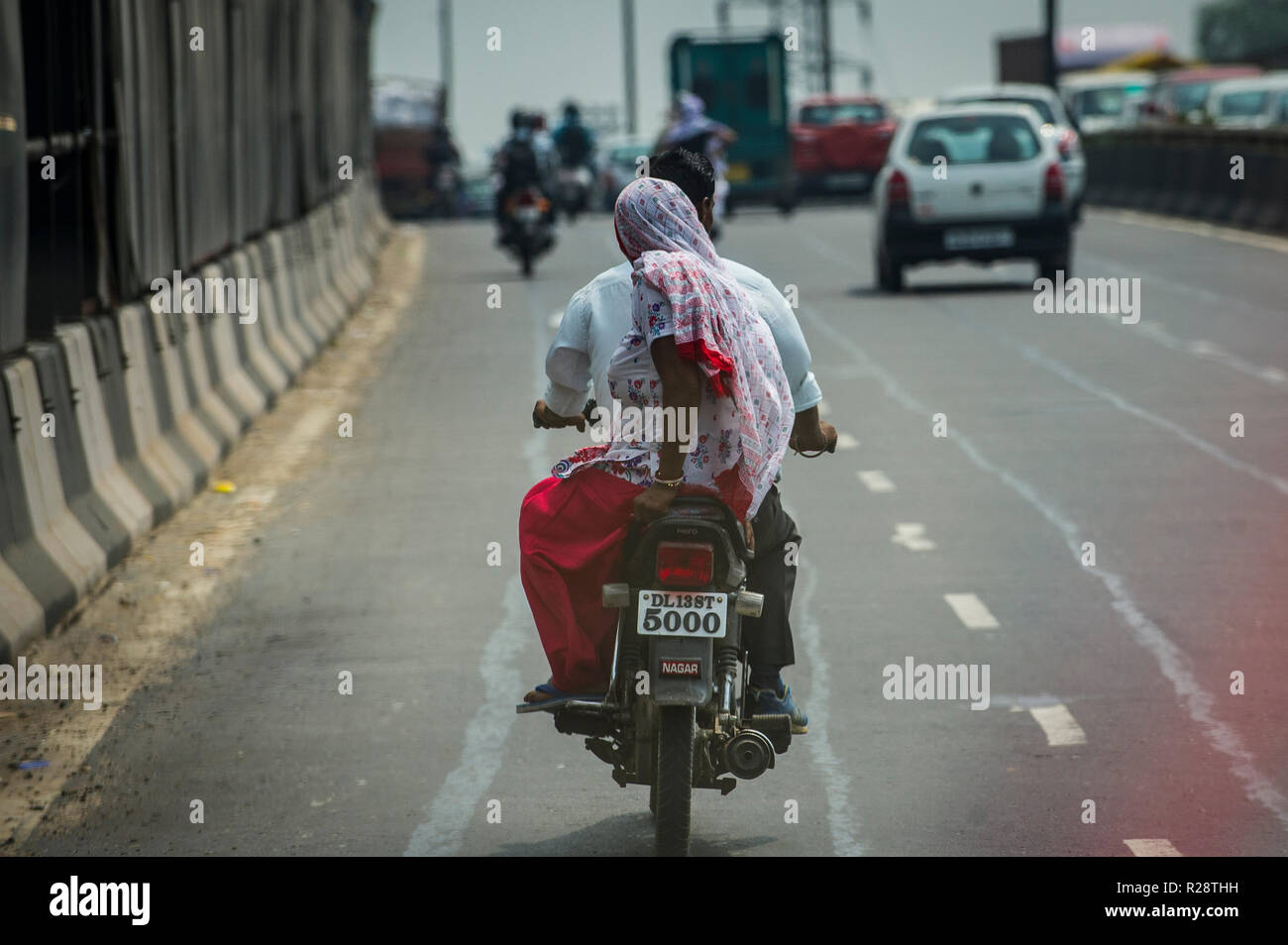 A woman rides pillion on a motorbike on a road in New Delhi, India ...