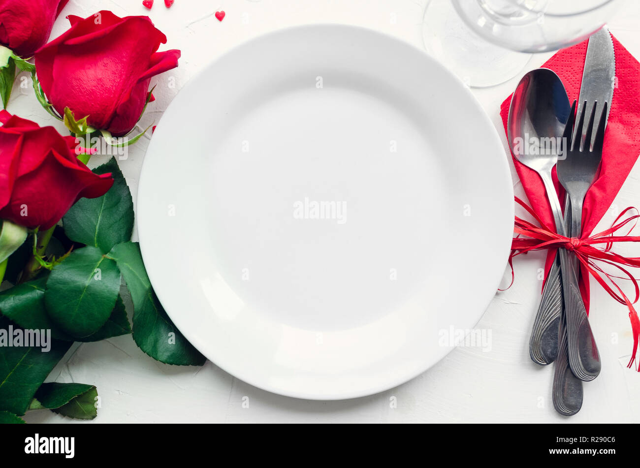 Valentine's Day romantic tabble setting with red roses, plates, cutlery ...