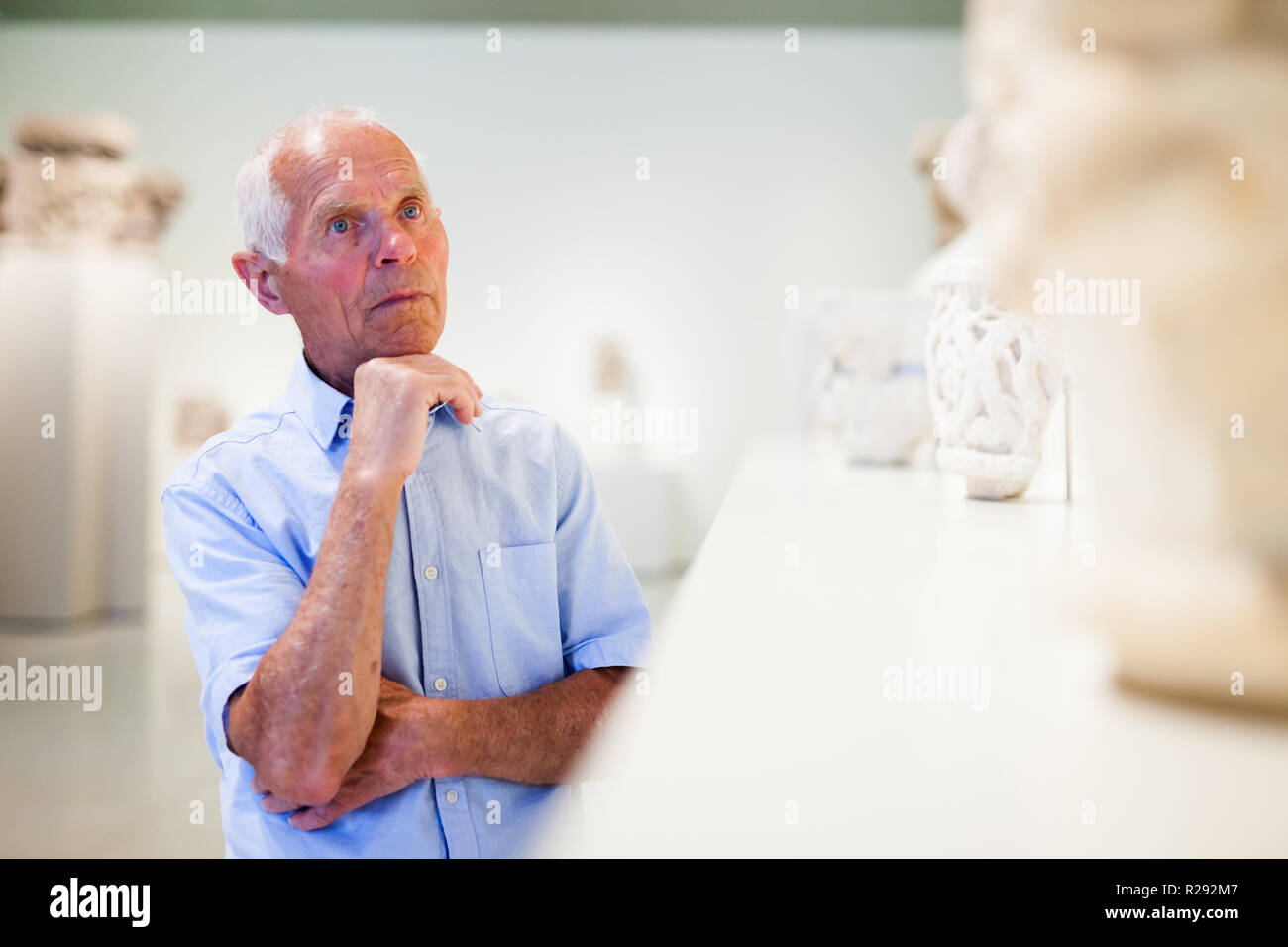 Attentive mature man observing sculptures exhibition in art museum ...