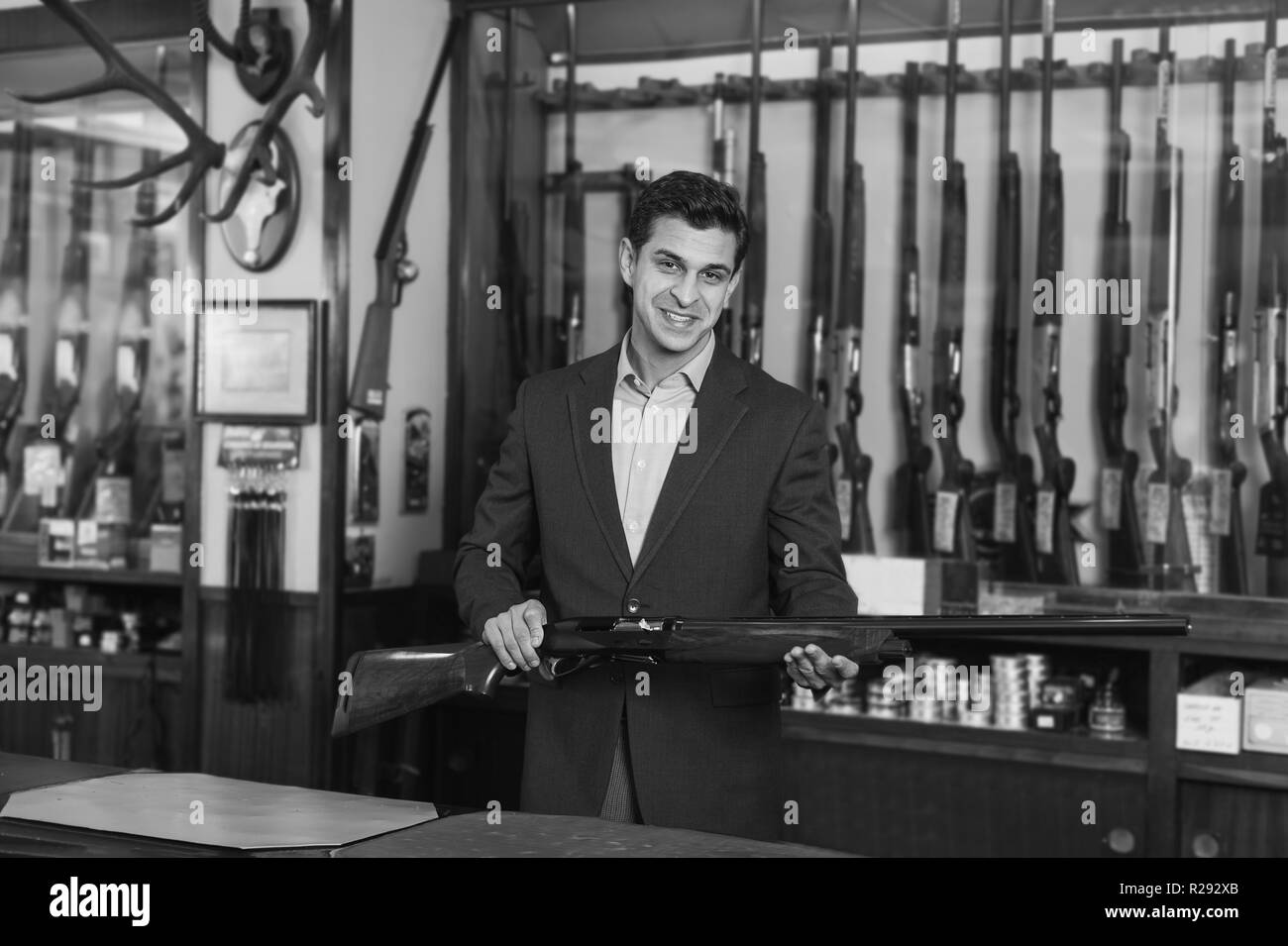 Portrait of positive salesman in gun store holding rifle Stock Photo ...