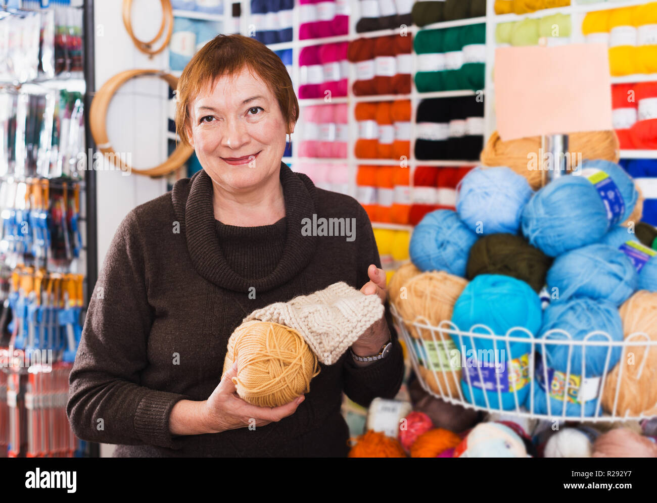 Positive woman picking yarn in color to knitted pattern in needlework ...