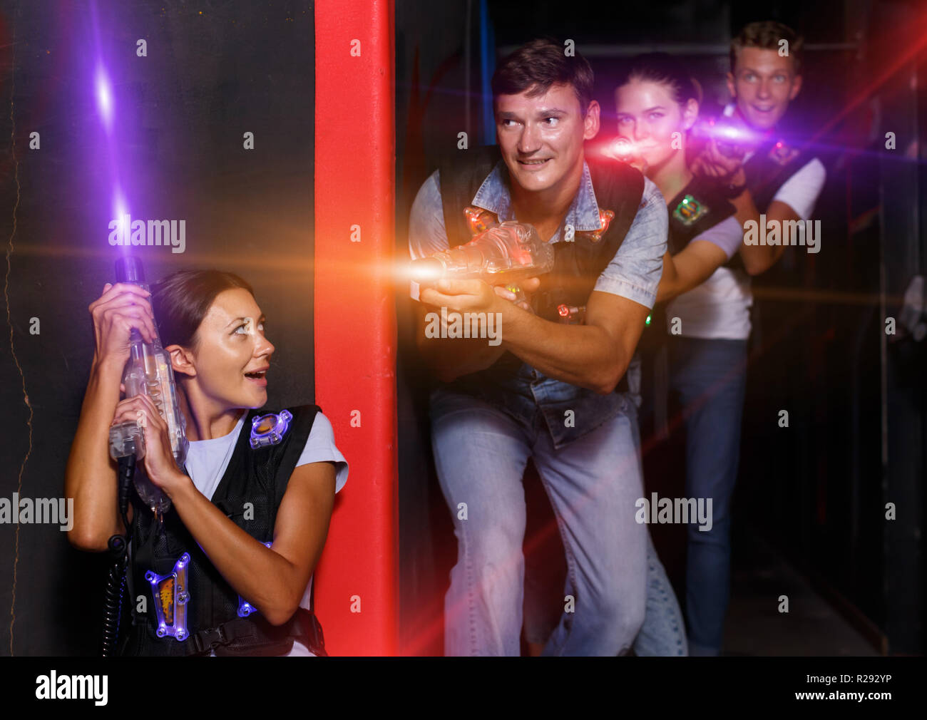 Group cheerful emotional people with laser guns playing laser tag game ...
