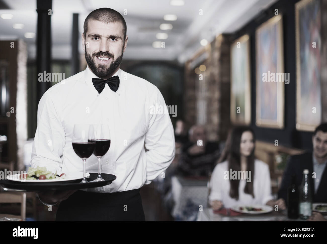 Professional friendly smiling waiter holding serving tray for ...