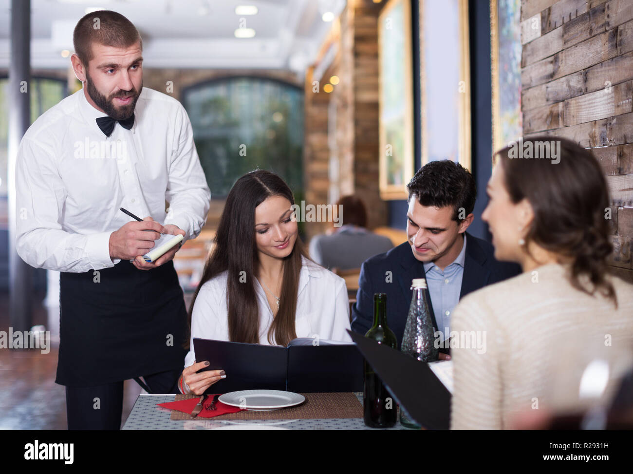Employee positive waiter man taking order from positive guests at ...