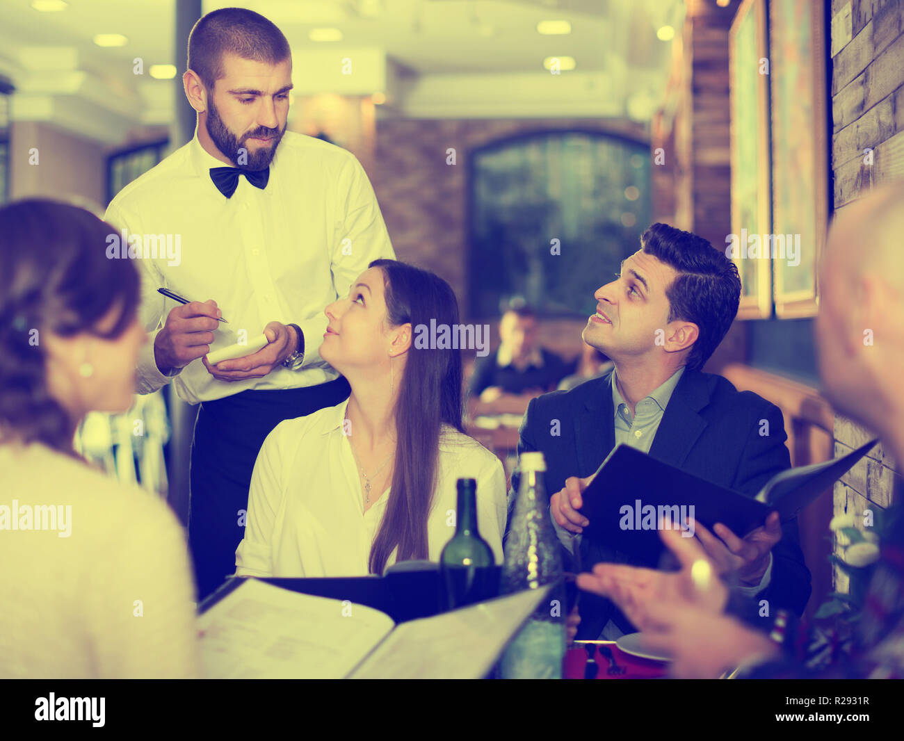 Employee smiling waiter man taking order from positive guests at ...