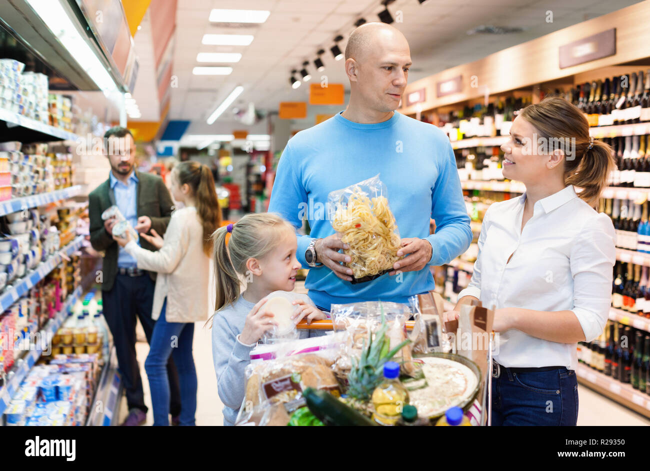 Happy positive family is looking on shelves with products in the ...
