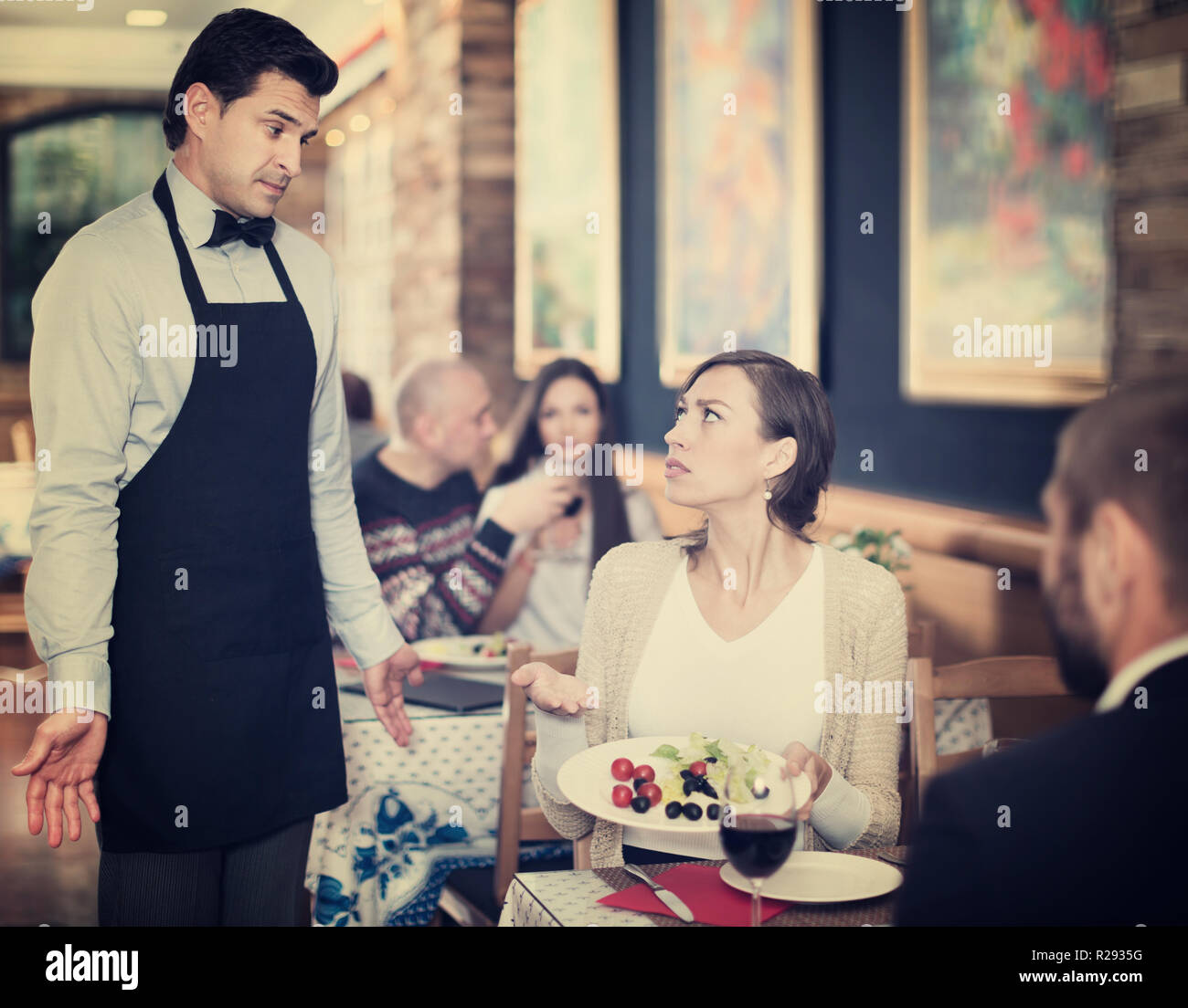 Adult couple expressing dissatisfaction with a waiter about the food ...