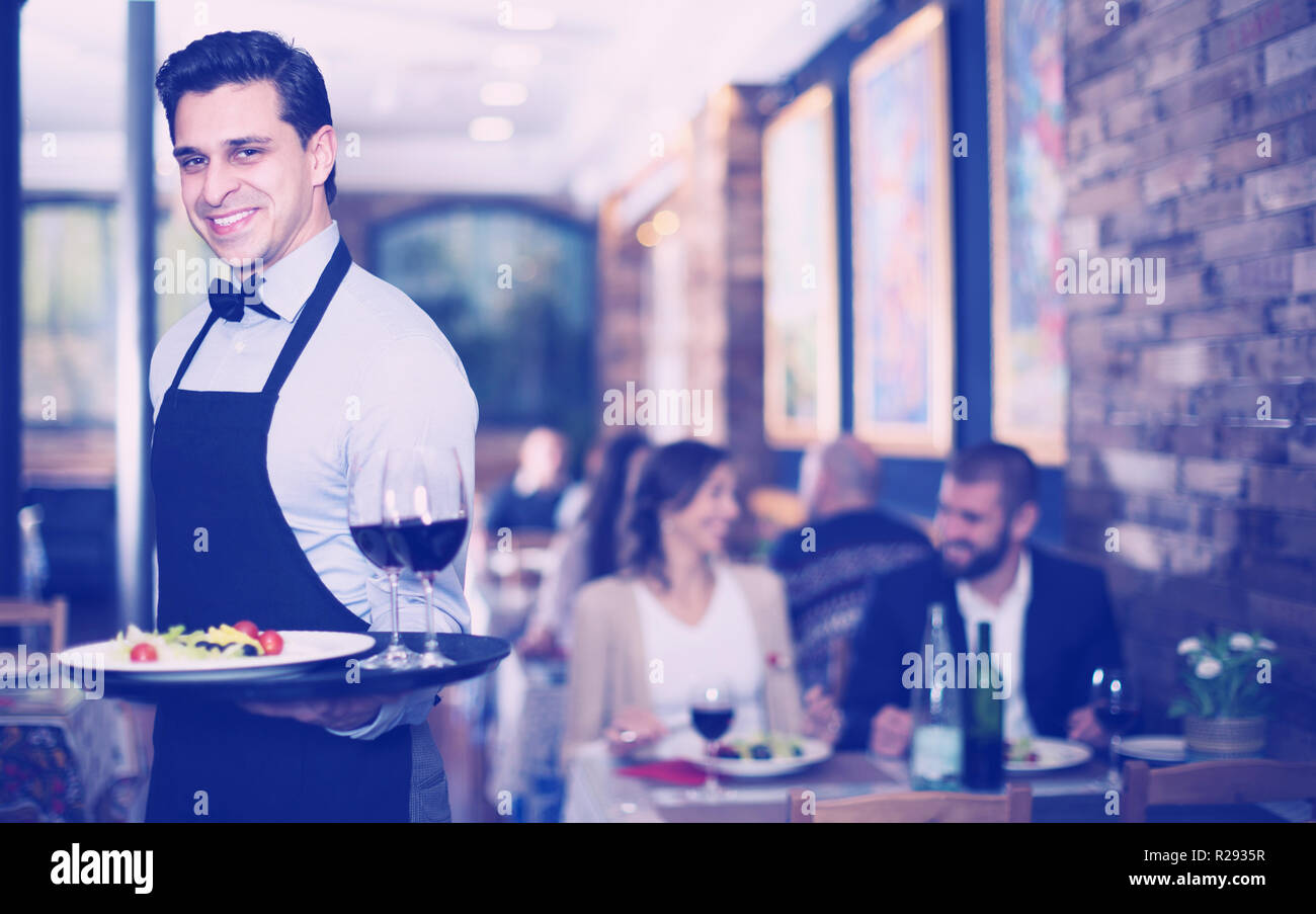 Adult cheerfful waiter standing with tray with glass and salad Stock ...