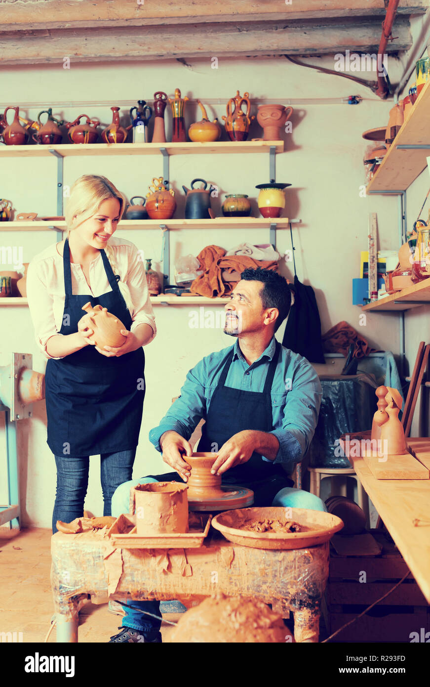 portrait of two cheerful potters working with pottery wheel in ceramics ...