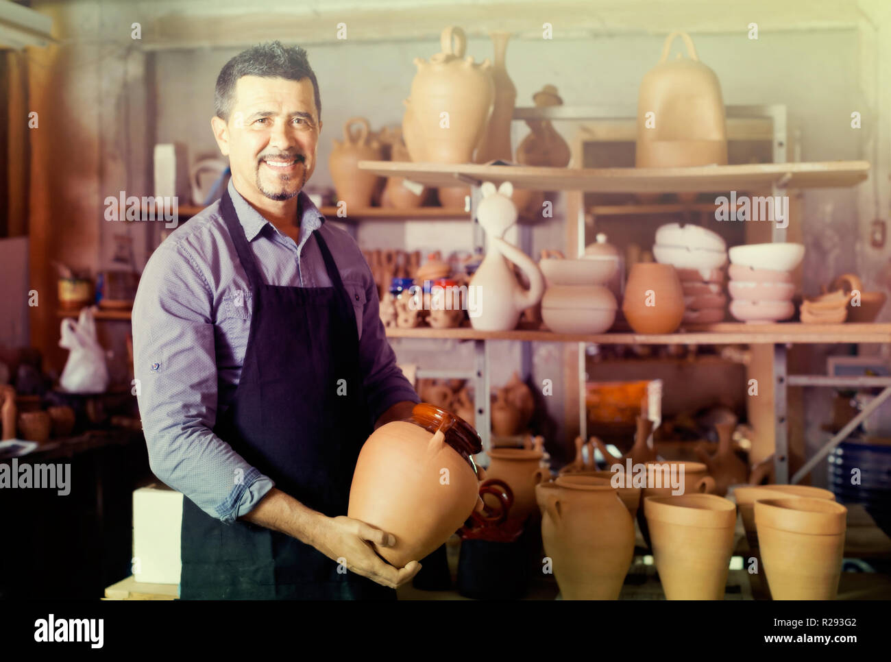 mature man potter holding ceramic vessels in atelier Stock Photo - Alamy