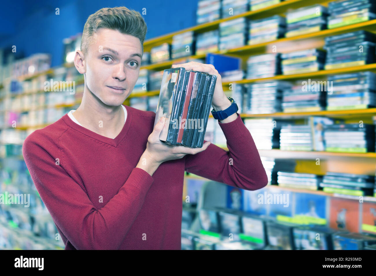 Young man choosing movies on DVD from large assortment at store Stock ...
