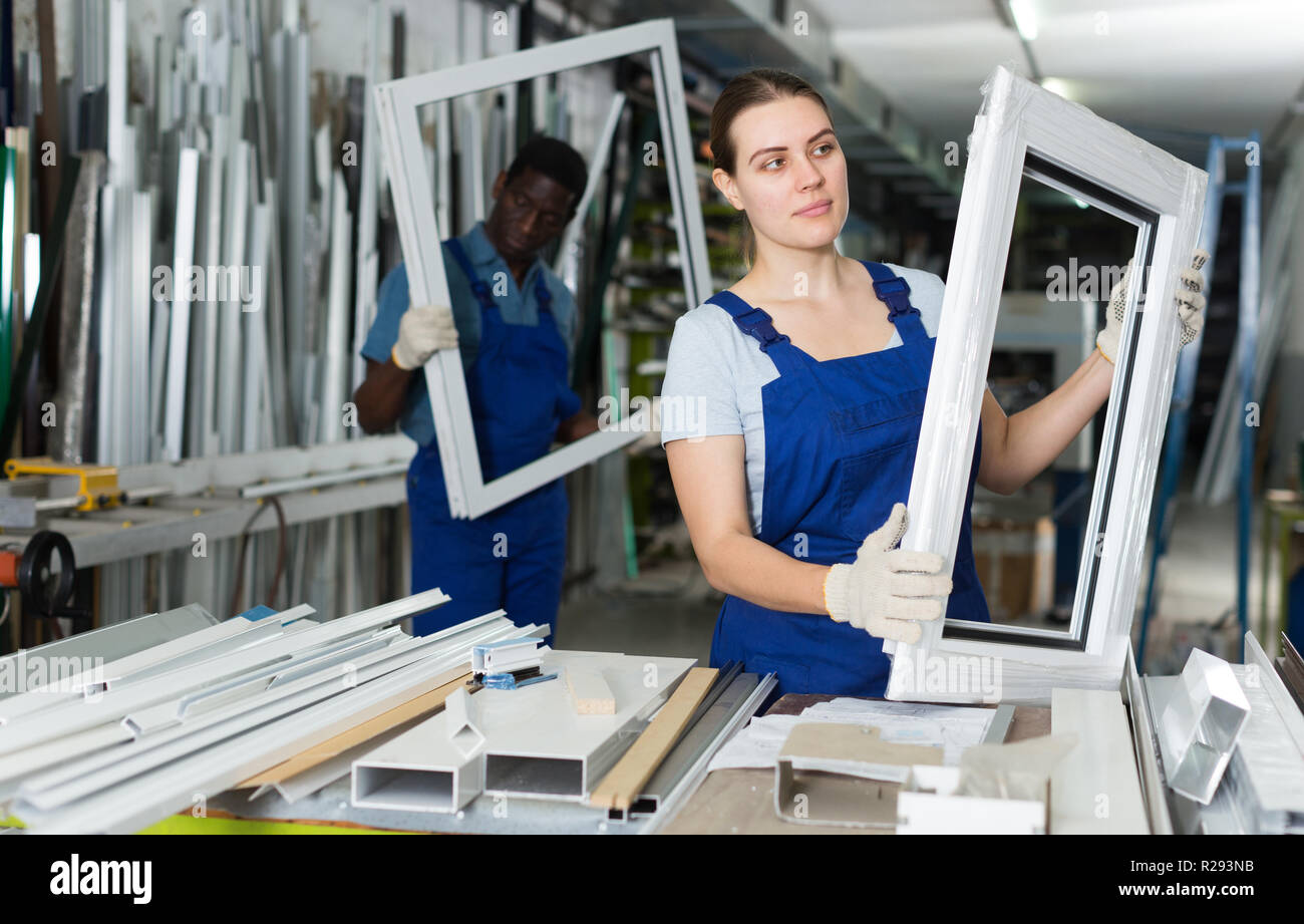 Female master is working with window frame in the window workshop Stock ...