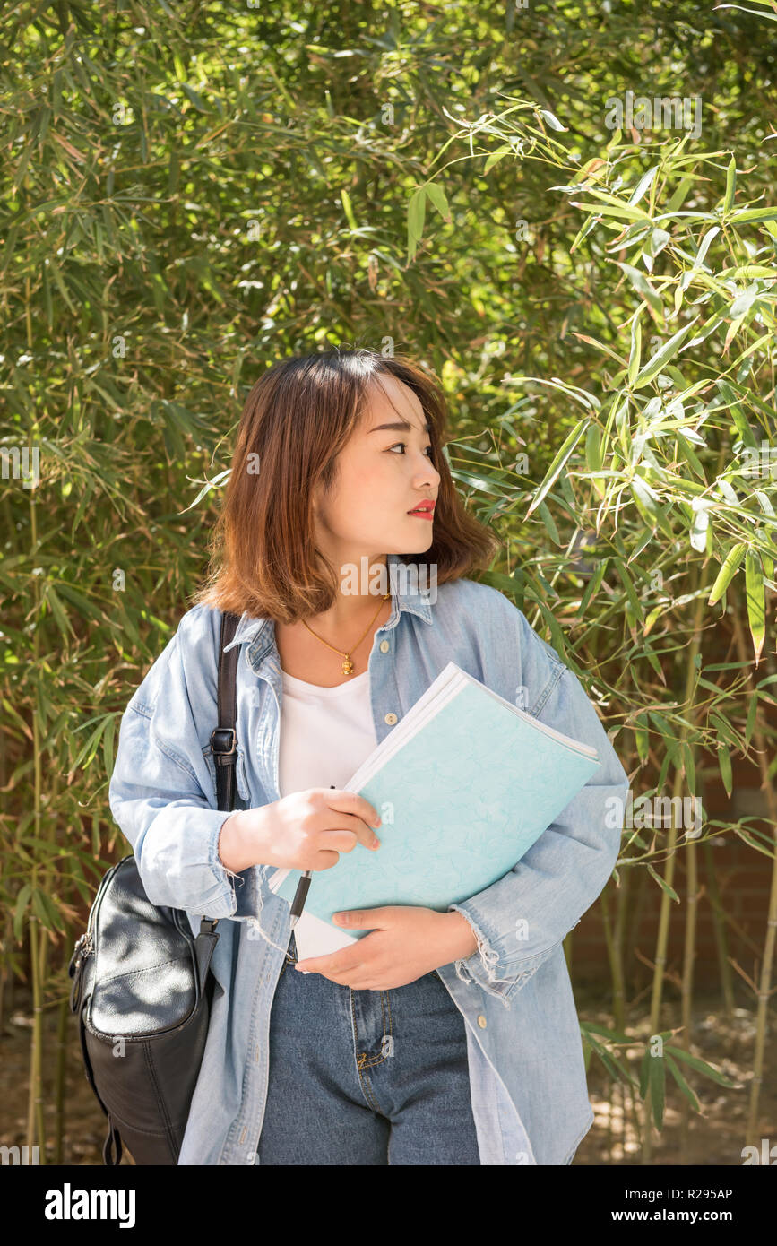 A beautiful college student carrying books at the campus. Female ...