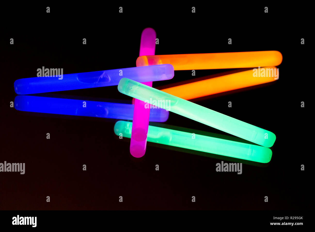 Colorful fluorescent light neon glow stick on mirror reflection black ...
