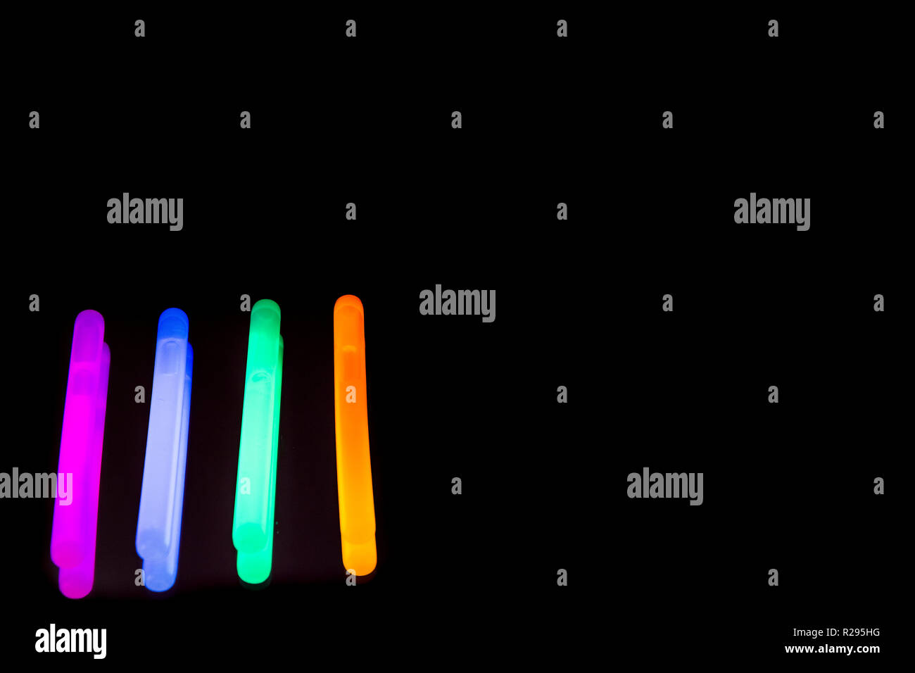 Colorful fluorescent light neon glow stick on mirror reflection black ...