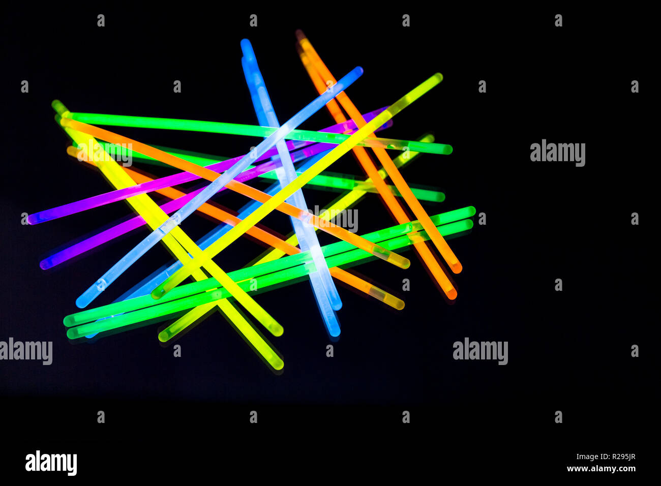 Colorful fluorescent light neon glow stick on mirror reflection black ...