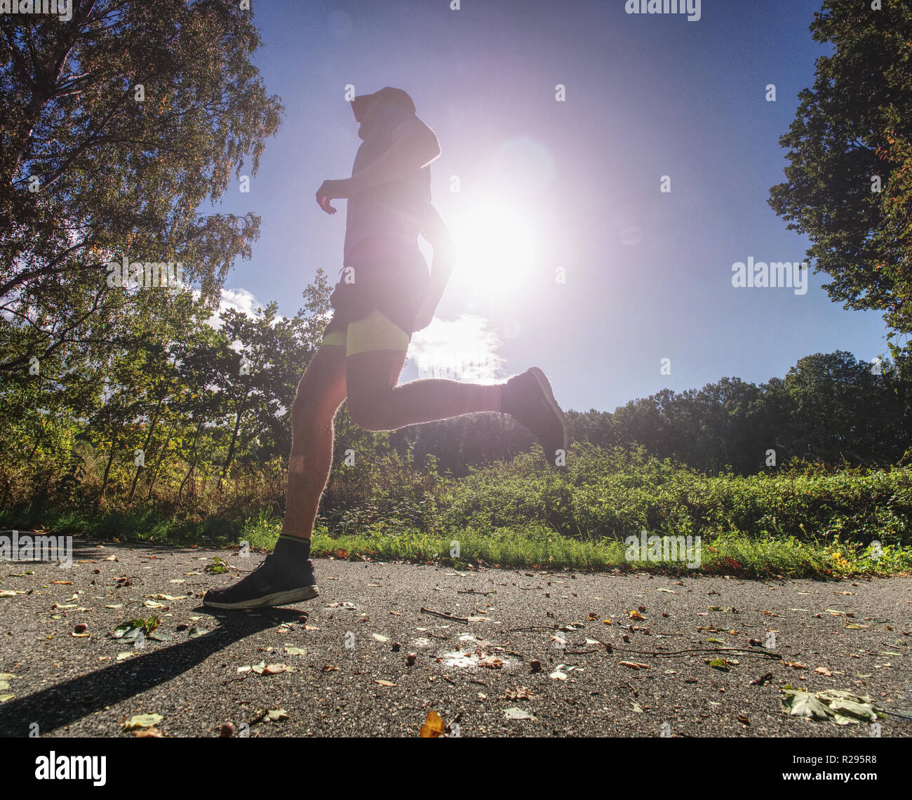 Slim body guy runs on path with fallen leaves. Warm day for outdoor ...