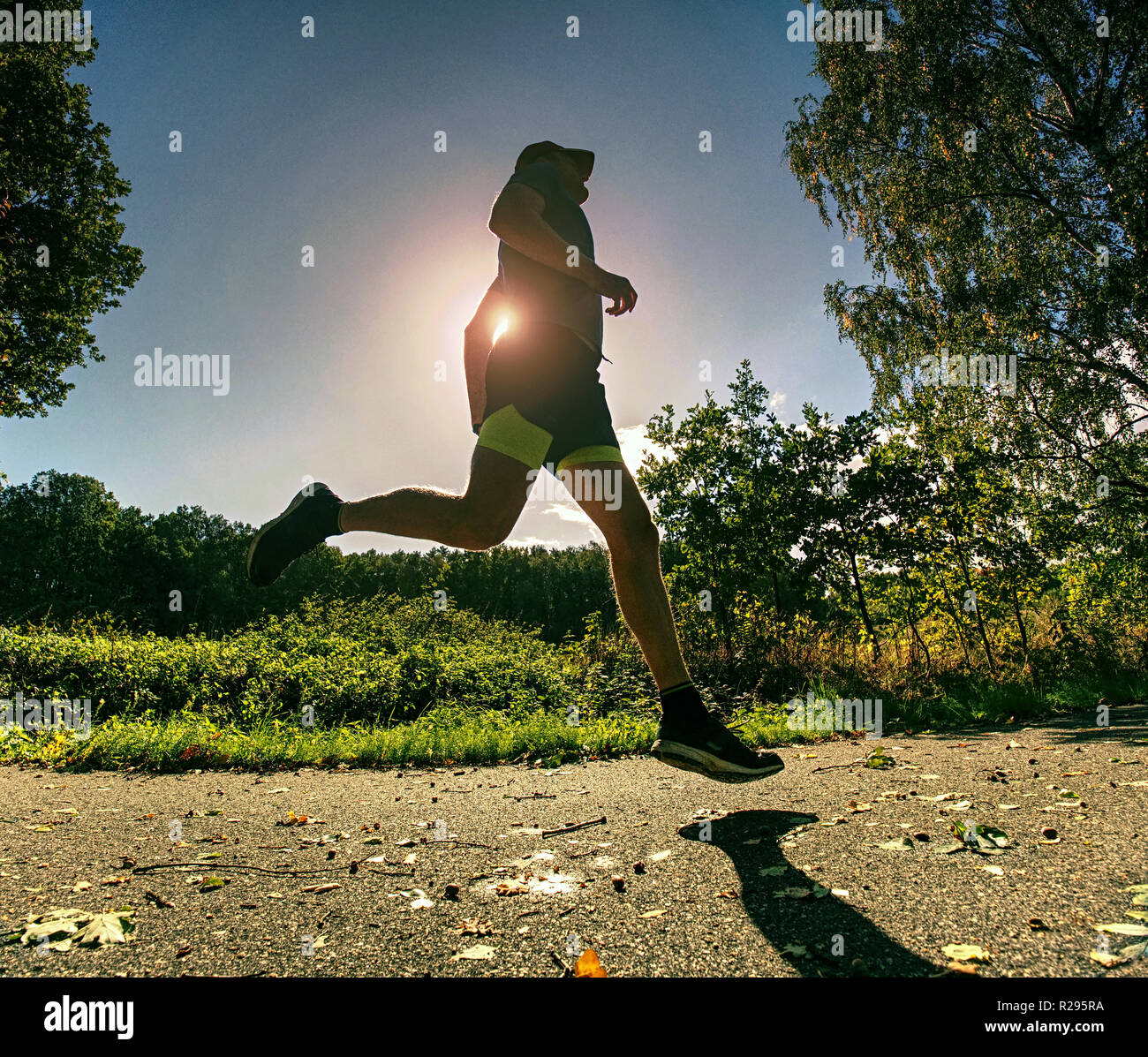 Slim body guy runs on path with fallen leaves. Warm day for outdoor ...