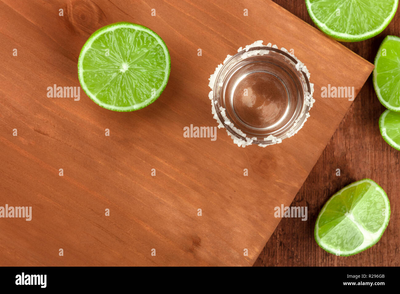 A tequila shot with lime slices, shot from above on dark rustic ...