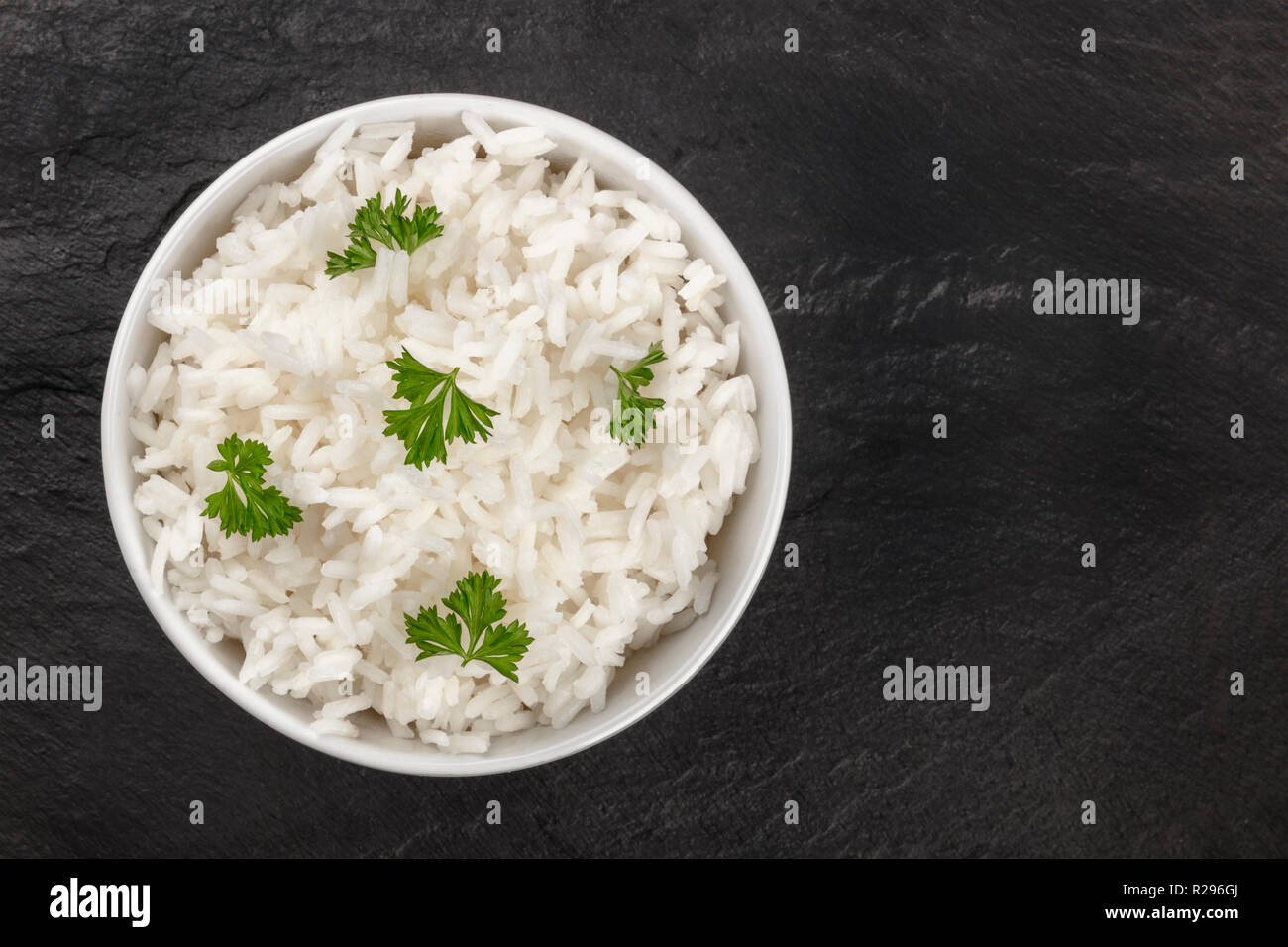 A bowl of boiled white long rice, shot from the top on a black ...