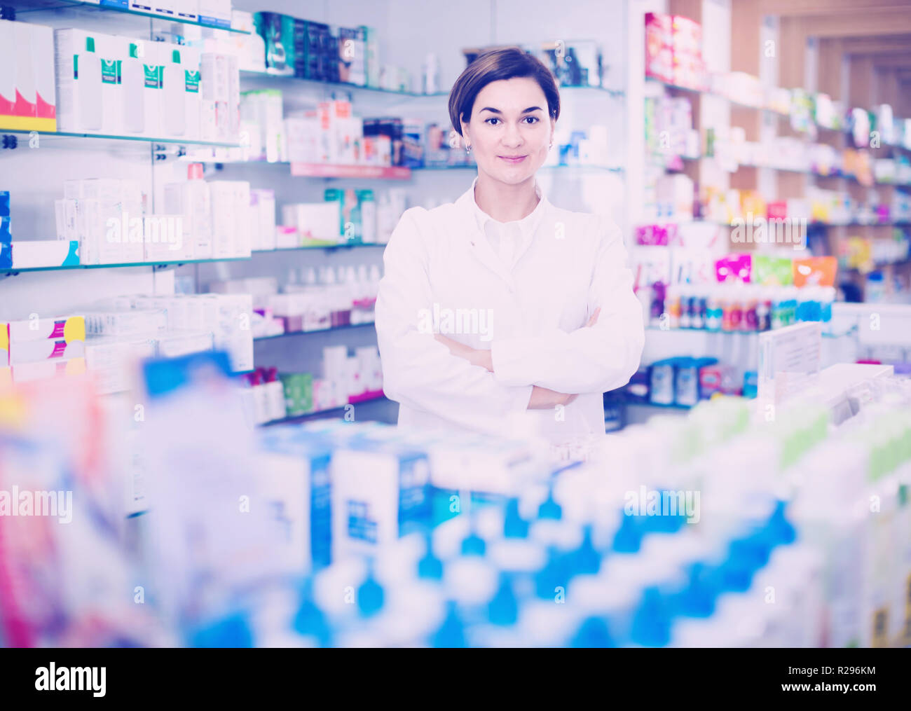 Young female pharmacist arranging displayed assortment in pharmacy ...