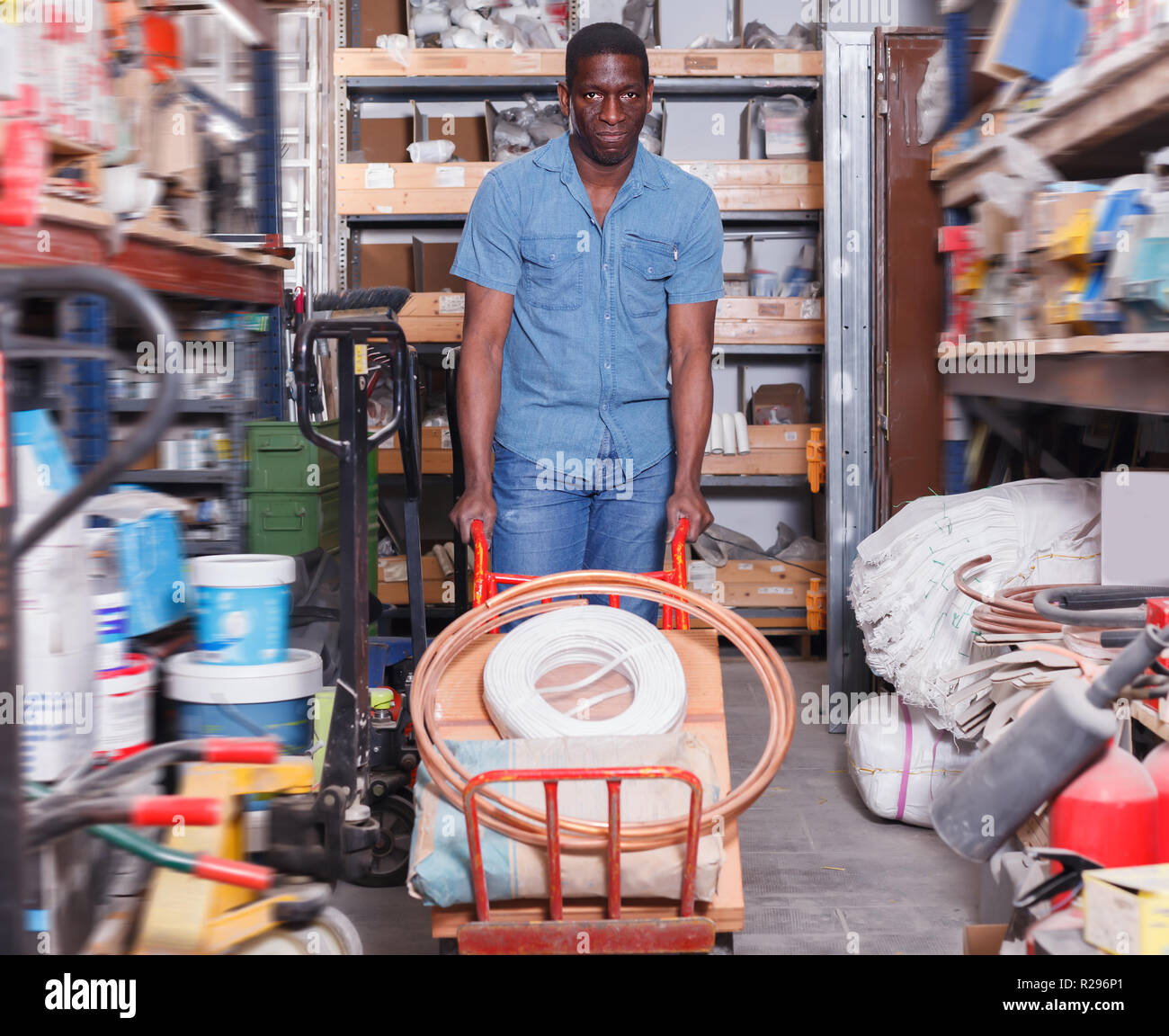 Adult African American pushing trolley cart with supplies for ...
