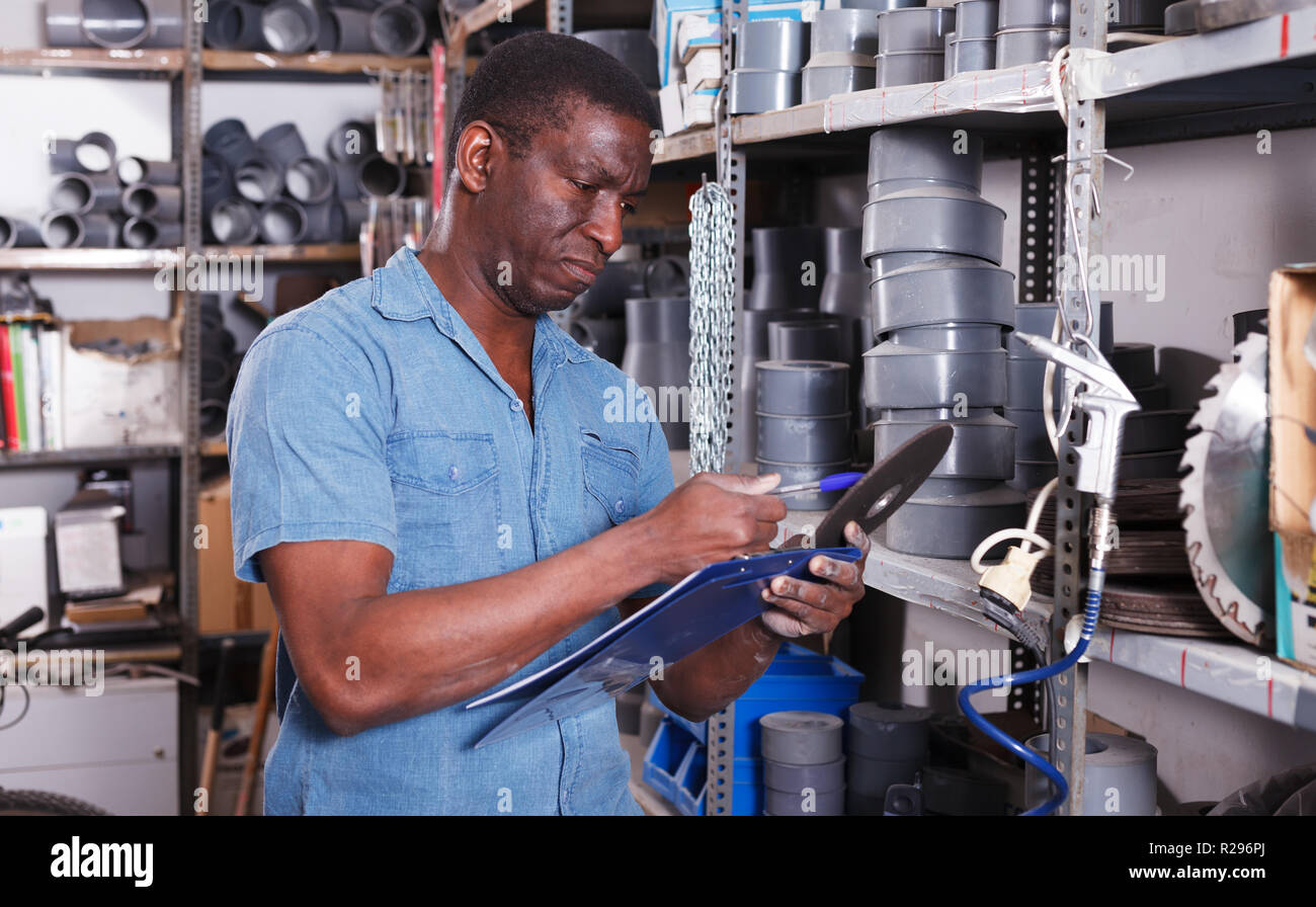 Confident African American salesman taking inventory of goods in ...