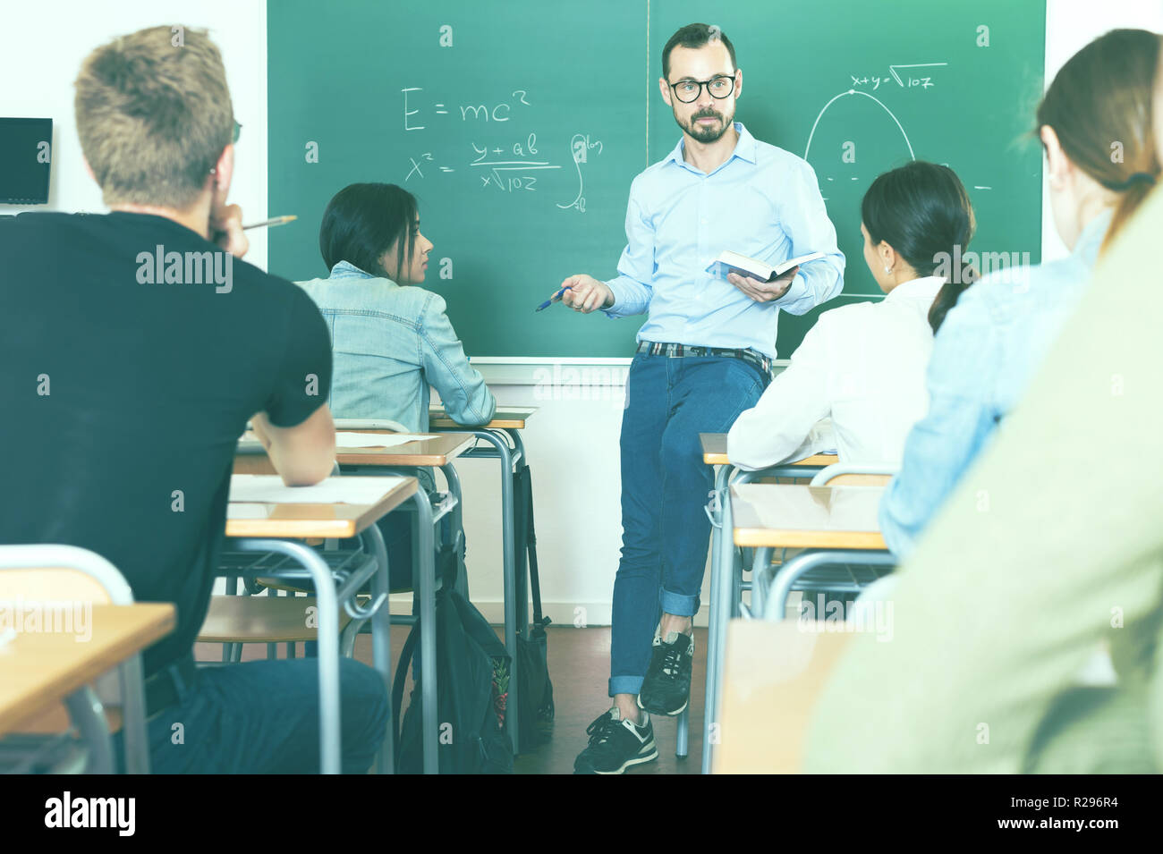 Positive male teacher is giving interesting lecture for students in the ...
