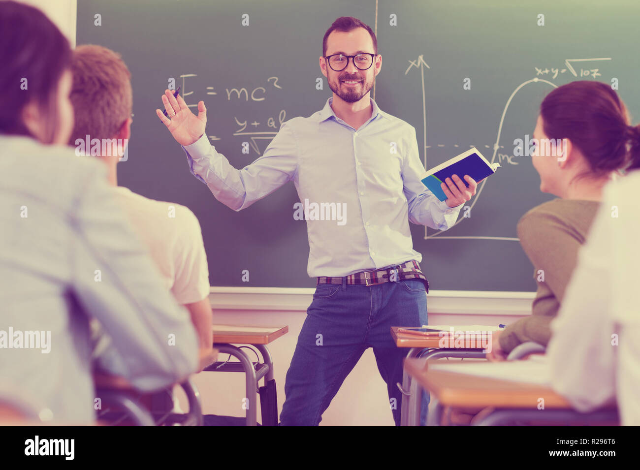 Happy young teacher is giving lecture for students in the class Stock ...