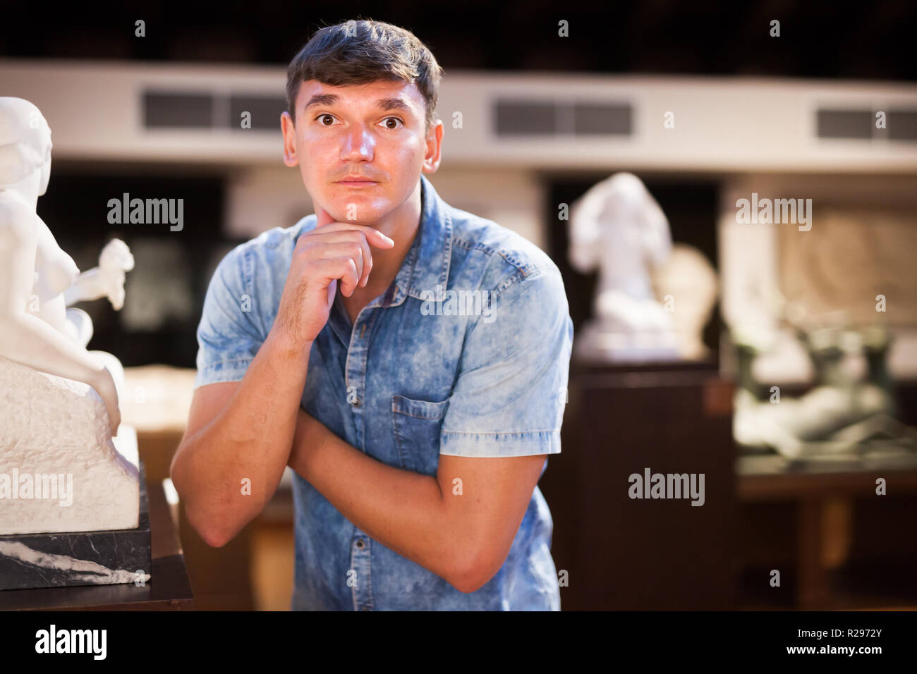 Man standing at hall of historical museum among exhibits of antiquity ...