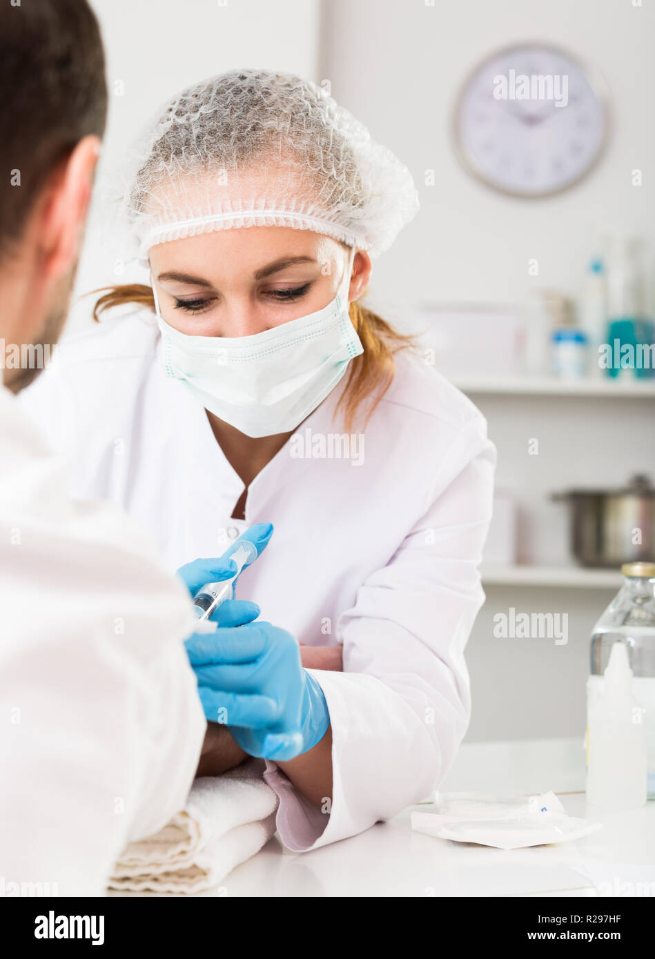 Female nurse using syringe to make injection to patient in hospital ...