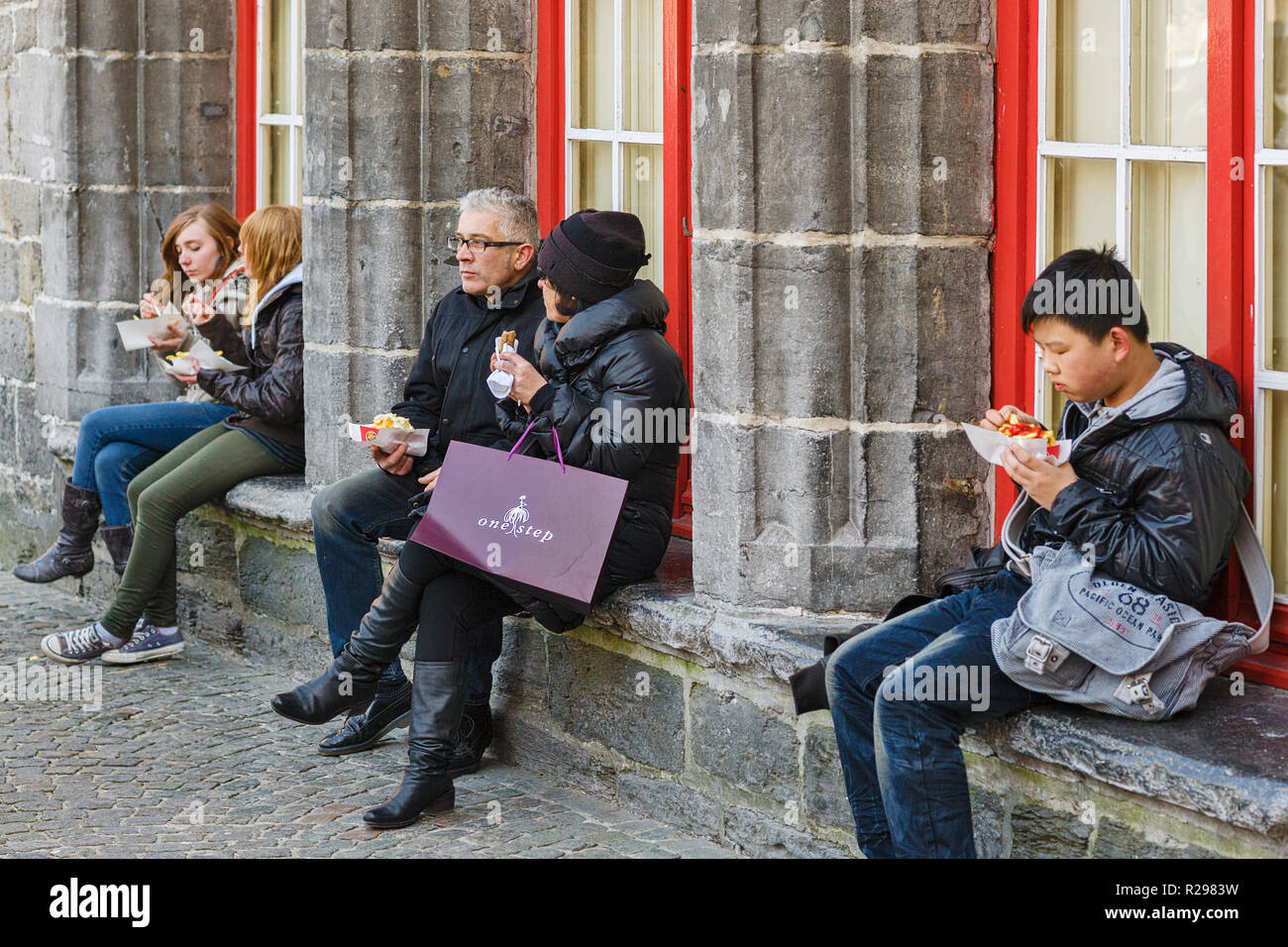 people eating french fries sitting on a window ledge of Bruges belfry ...