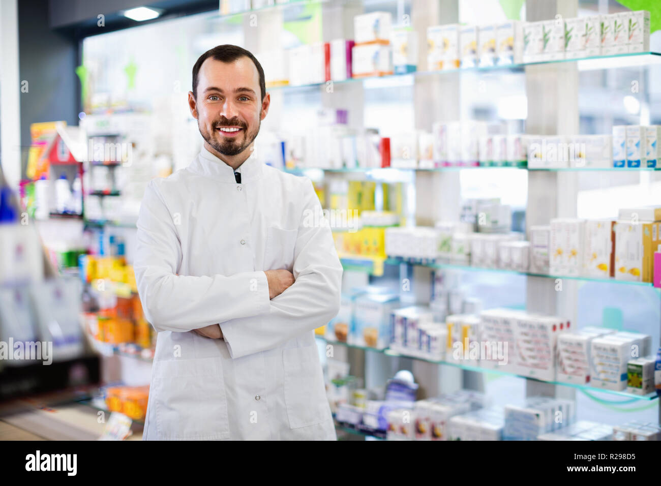 Smiling happy positive male pharmacist demonstrating assortment of ...