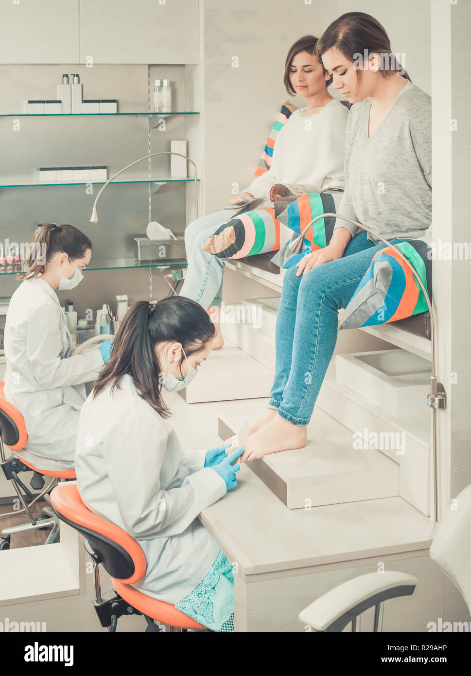 Pair of smiling women clients getting pedicure in modern nail salon ...