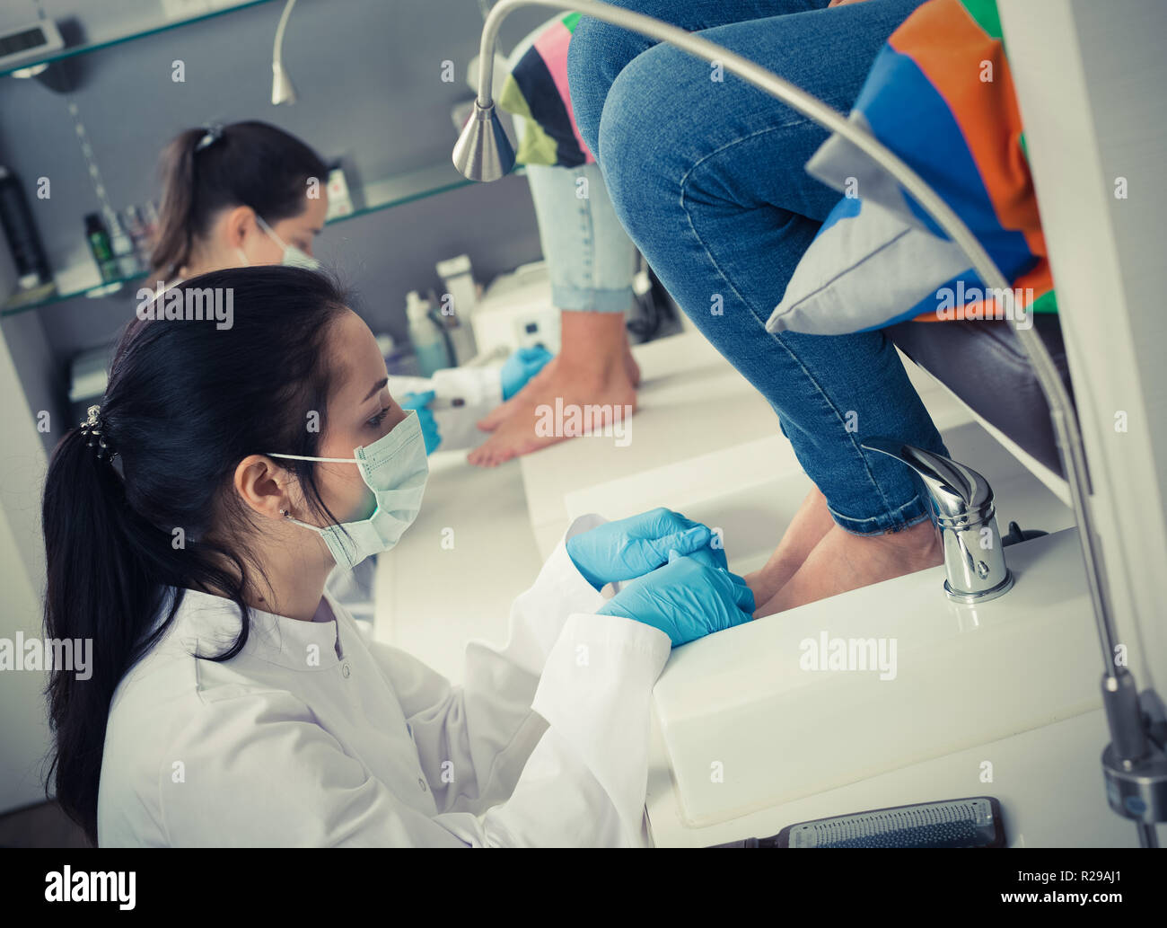 Nail pedicure technician performing procedure for foot care in beauty ...